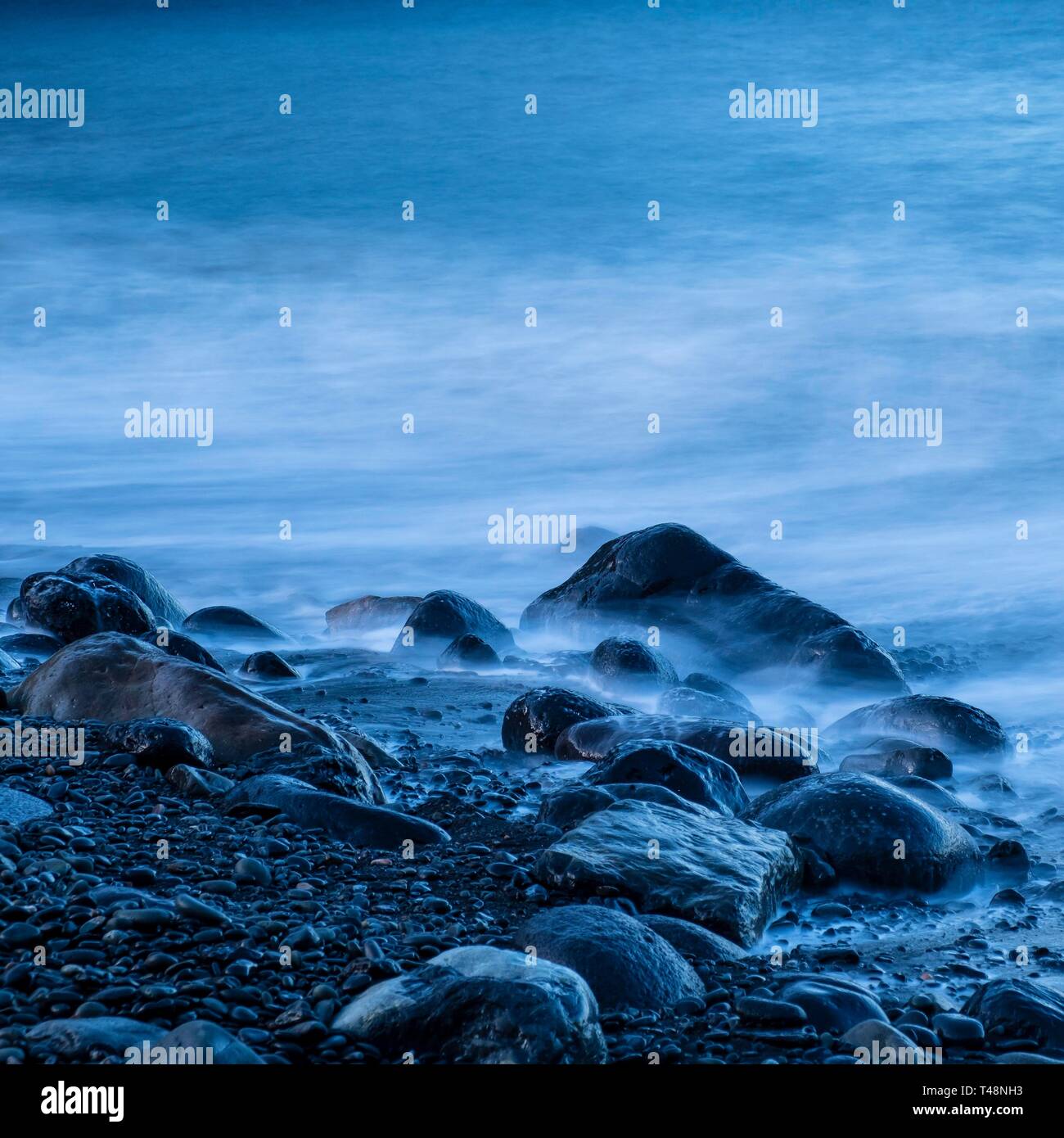 Black stones in the water on the beach, sea, surf, time exposure, La ...