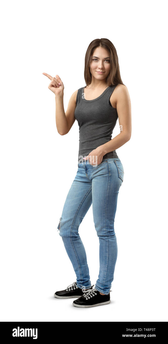 Young woman in sleeveless top and jeans standing in half-turn with left ...