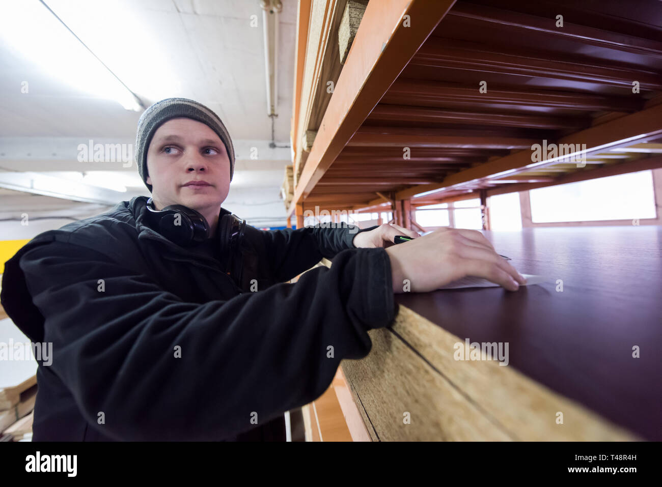 young man carpenter using pen while writing a receipt in big modern ...