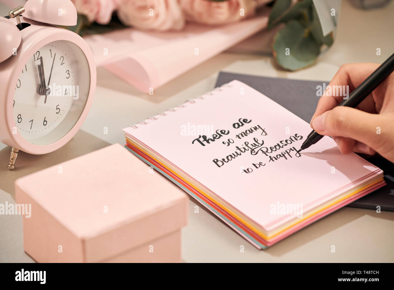 Woman hands holding pen, ready to write. Pink rose, pen and gift with ...