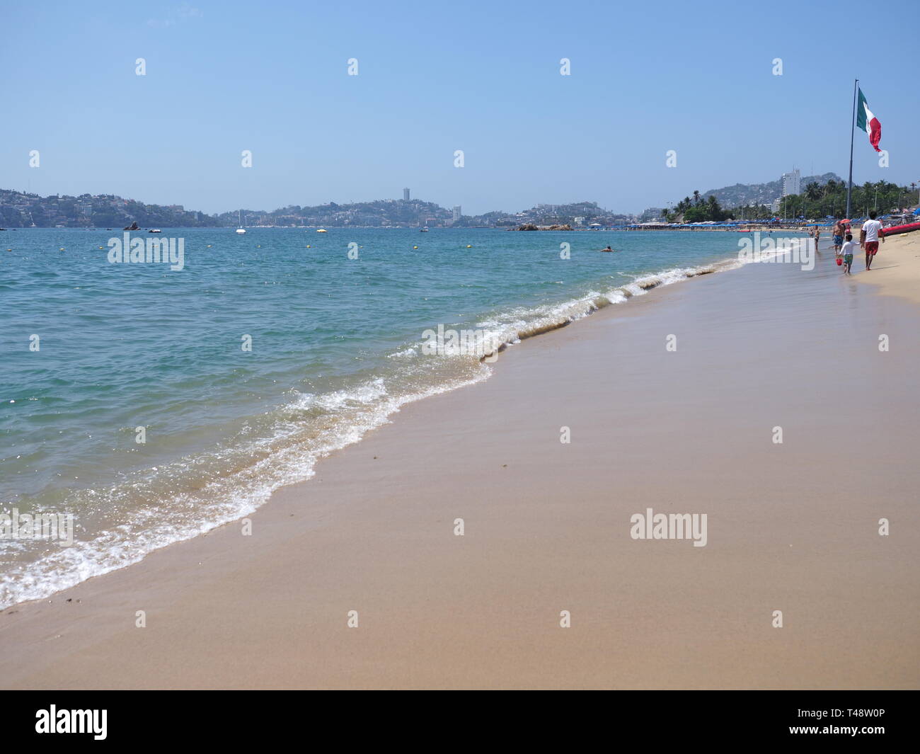Scenic landscape with large mexican national flag and sunbeds at bay of ...