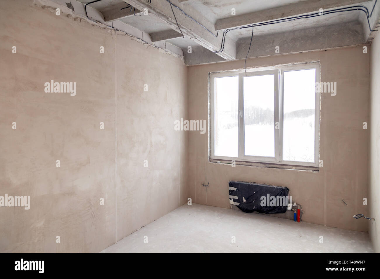 Empty room with a window and a battery in a house under construction ...