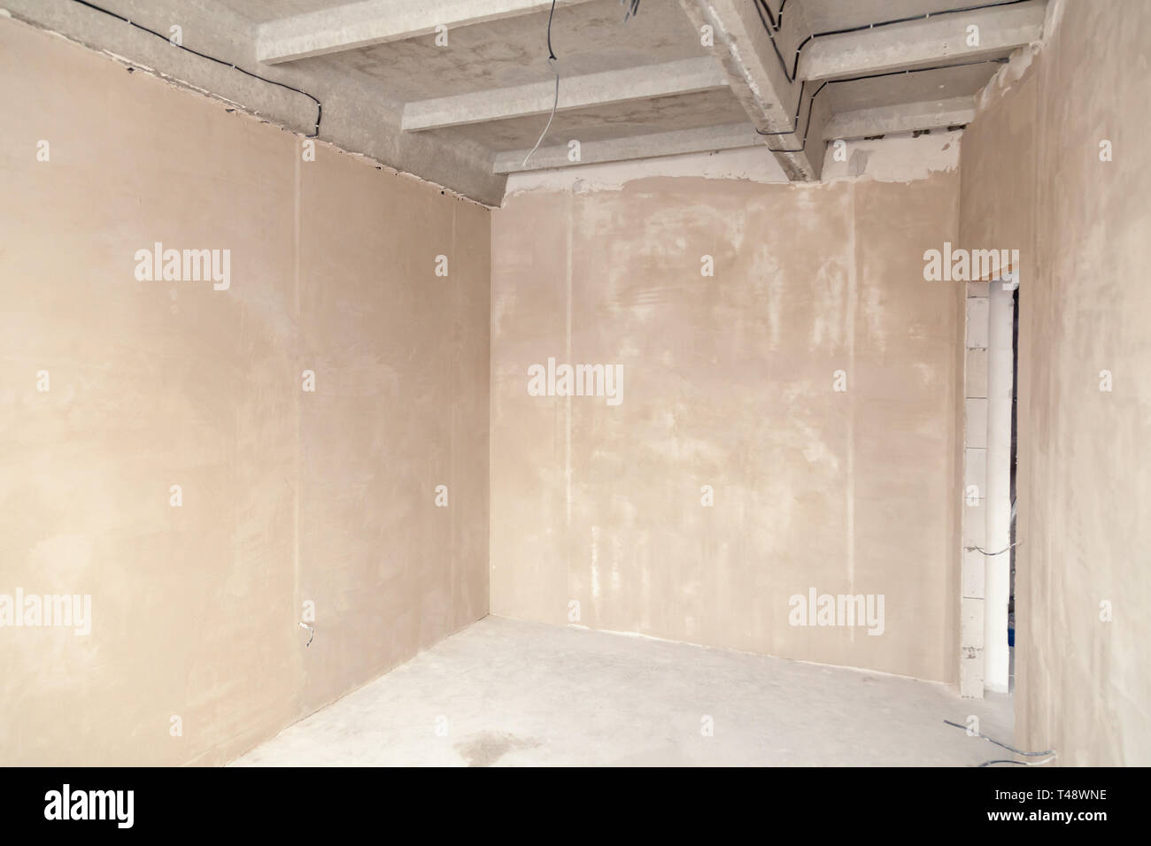 Empty room in a house under construction, plastered walls, screed on ...