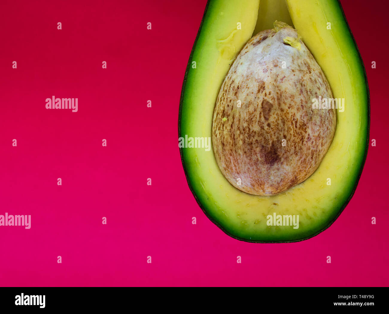 Half cut avocado with seed on magenta pink background. Vivid vibrant ...