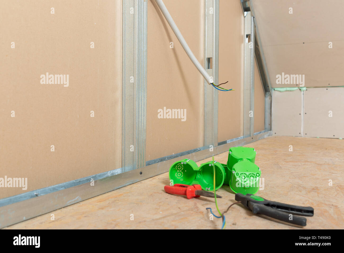 Electricity wire installation into plasterboard wall in attic. Attic ...