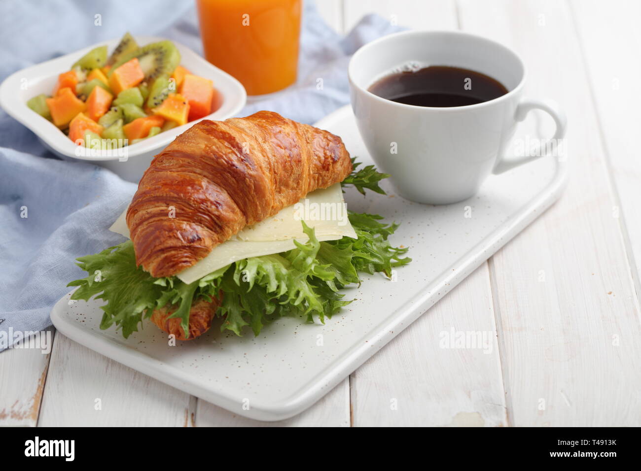 French breakfast: croissant sandwich with cheese, fruit salad, and a ...