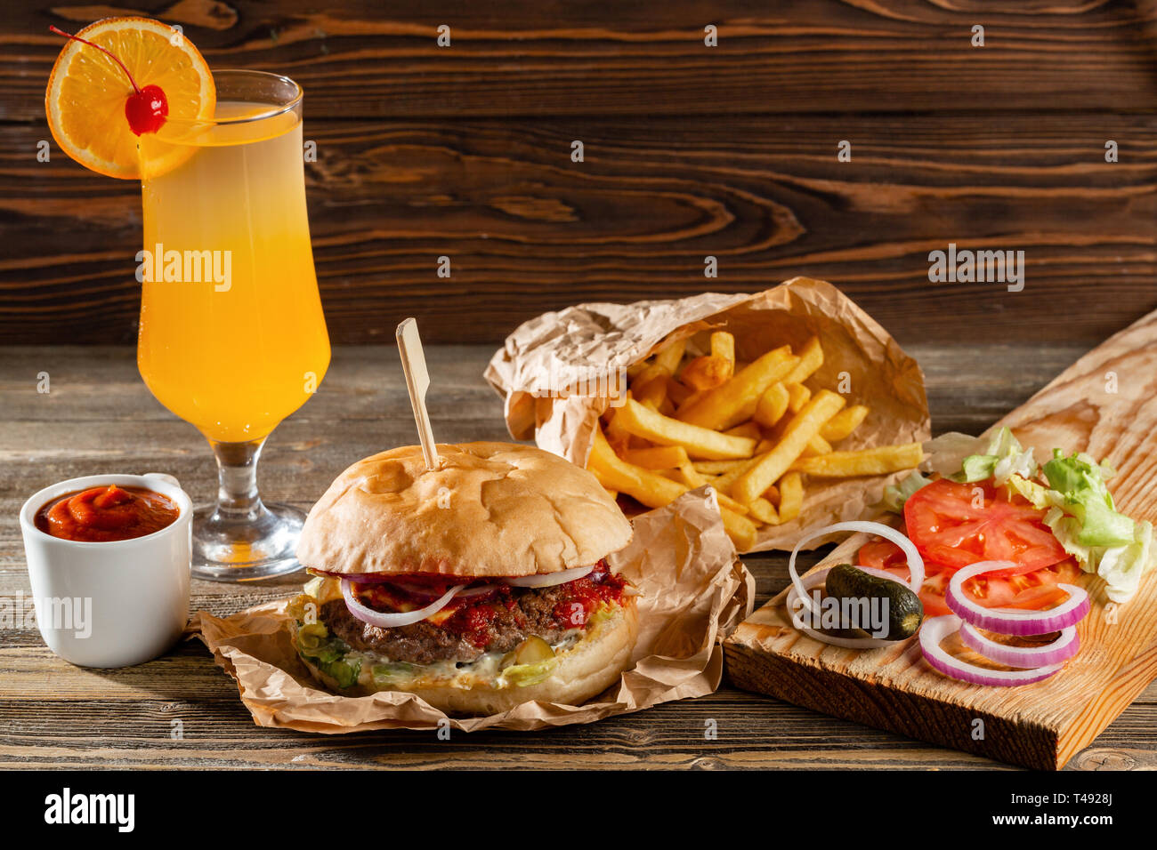 Big lunch. Burger with beef BBQ and fries. Glass of orange juice on a ...
