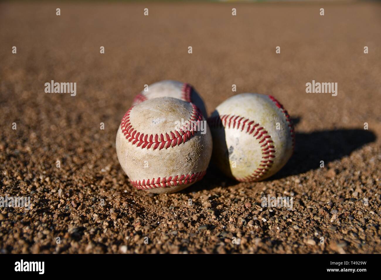 Photo of three game used baseballs on a baseball infield on a sunny day ...