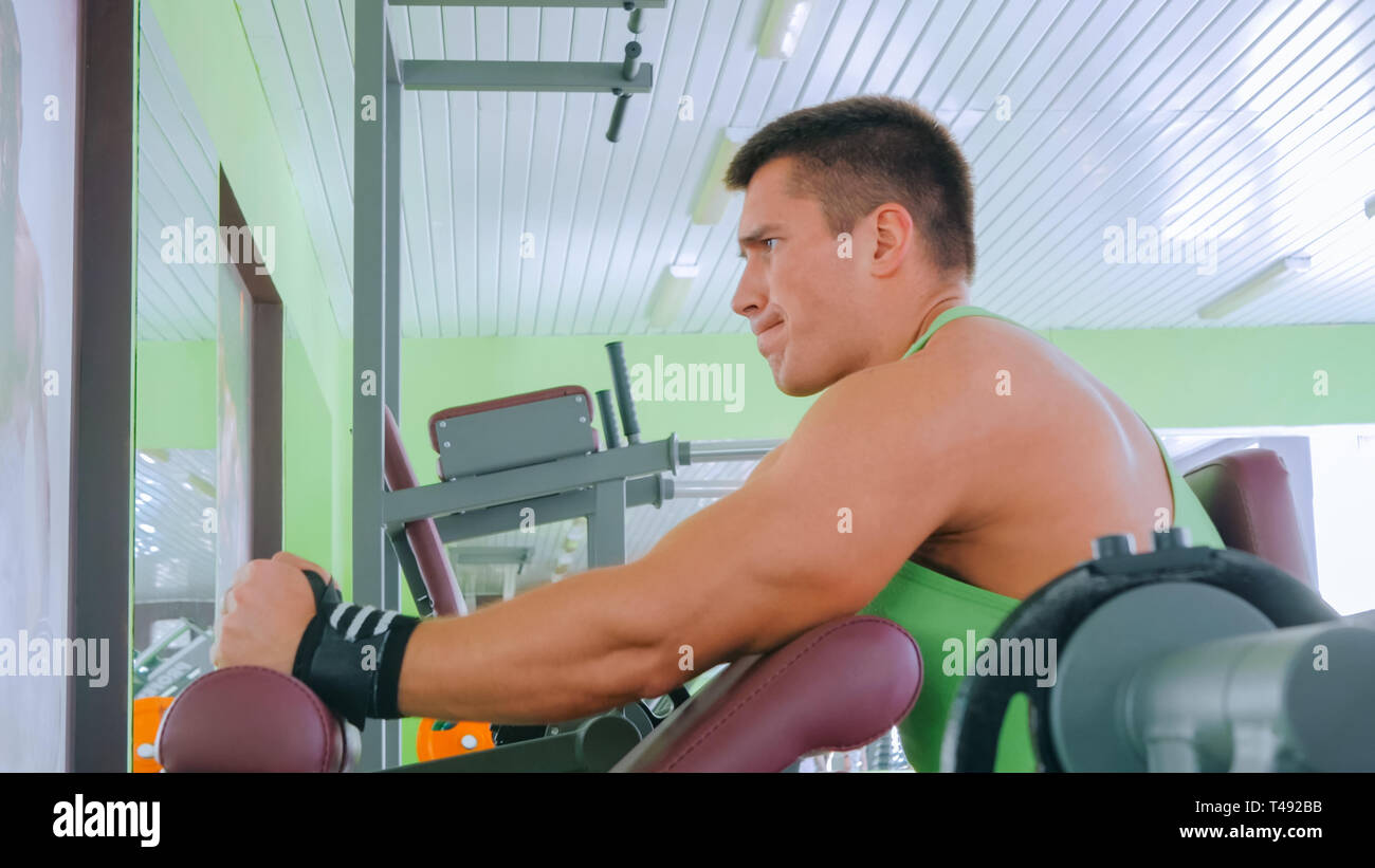 Athletic young man working out on fitness exercise equipment at gym ...