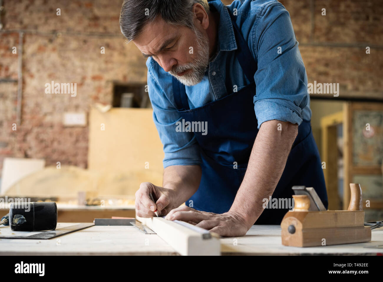 Mature handsome joiner work in carpentry. He is successful entrepreneur ...
