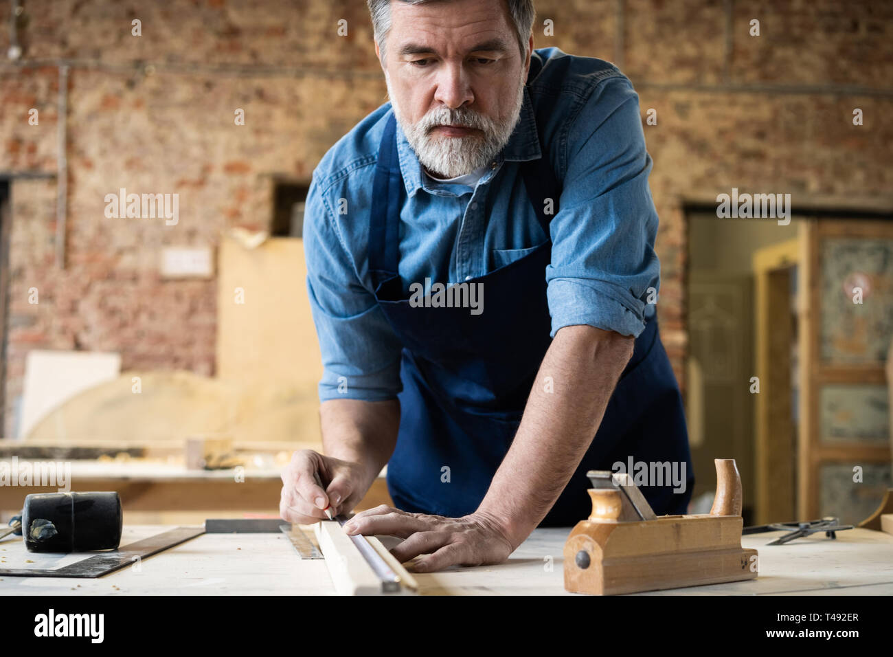 Mature handsome joiner work in carpentry. He is successful entrepreneur ...