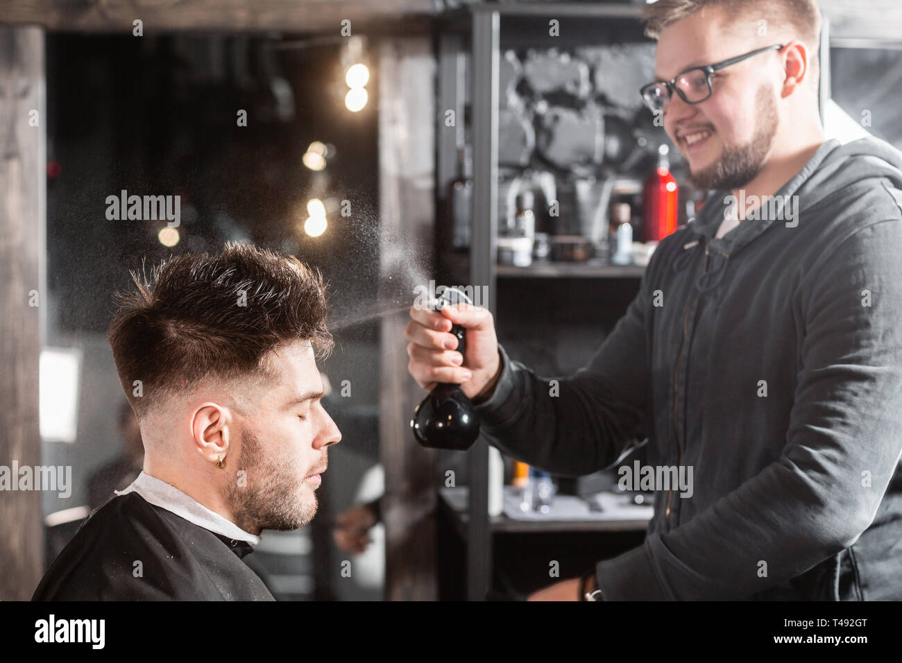 Barber sprays clean water on head in barbershop. Professional trimmer ...