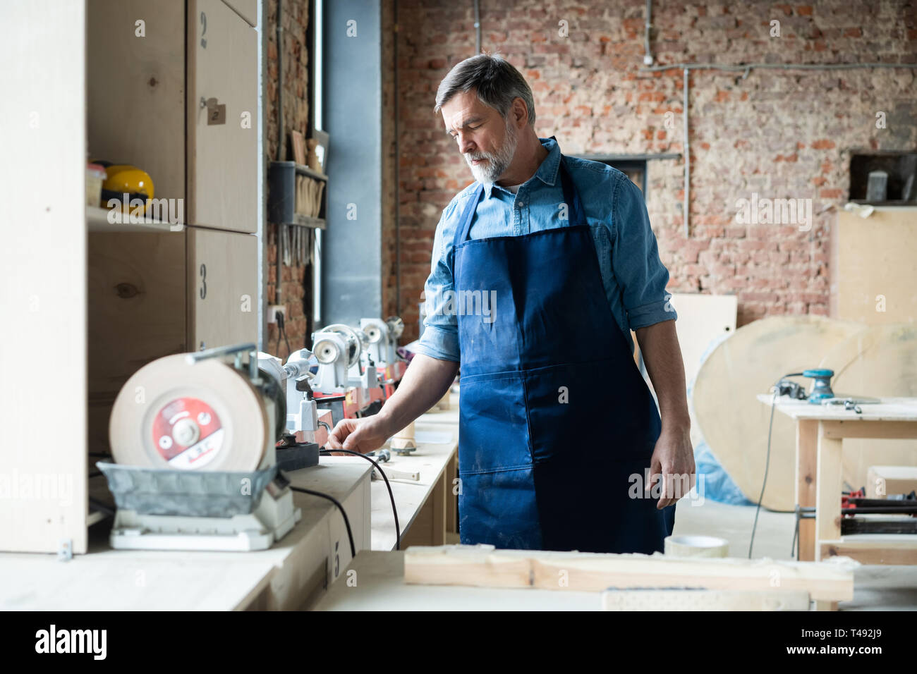 Mature handsome joiner work in carpentry. He is successful entrepreneur ...