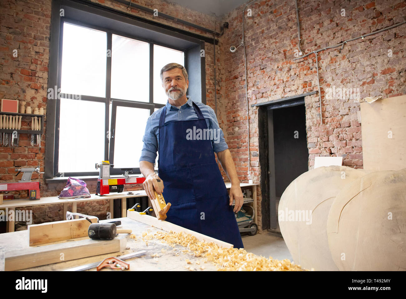 Mature handsome joiner work in carpentry. He is successful entrepreneur ...