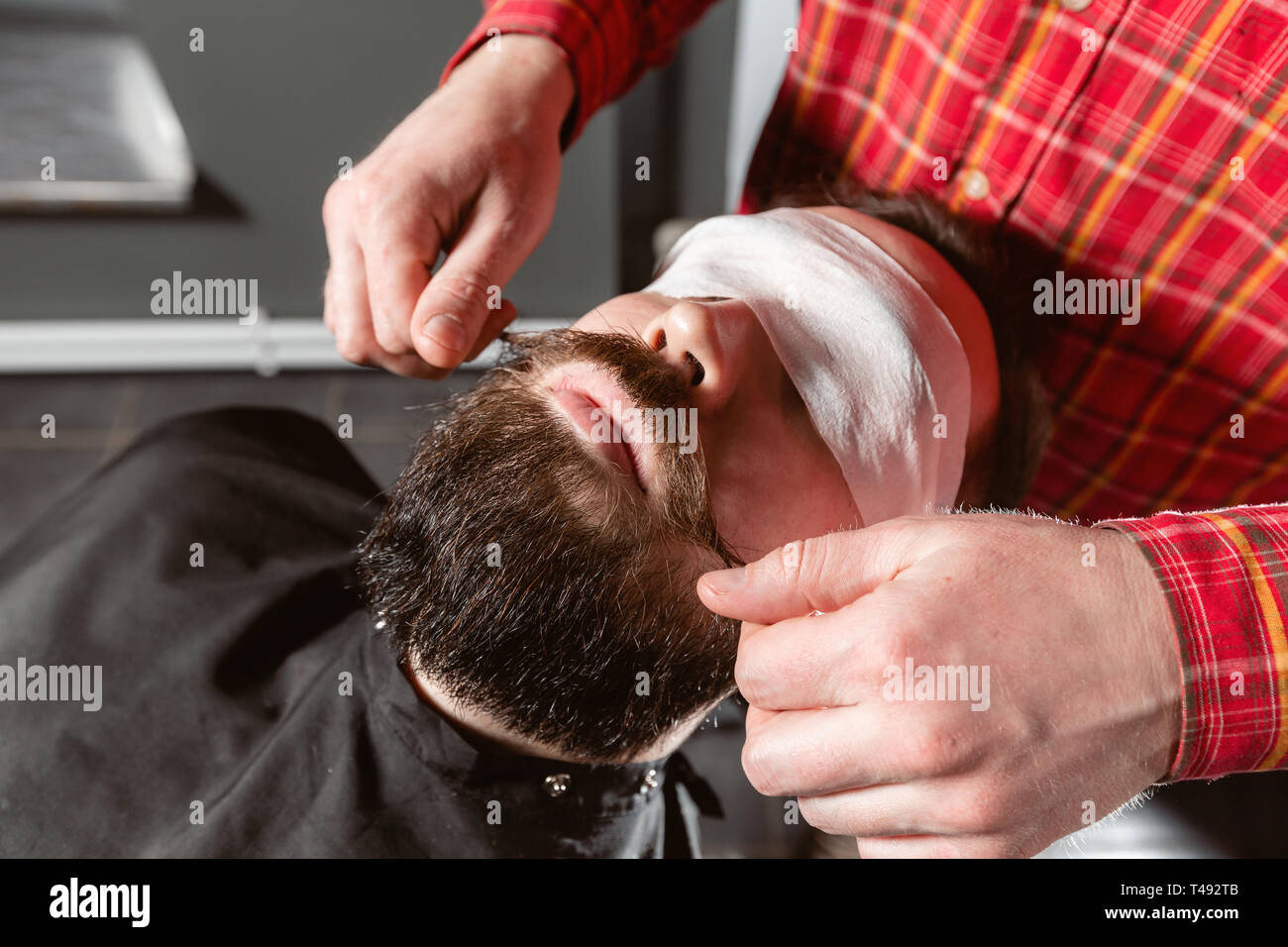 Barber is making the beard shape. Beard cutting, face care. Work in ...