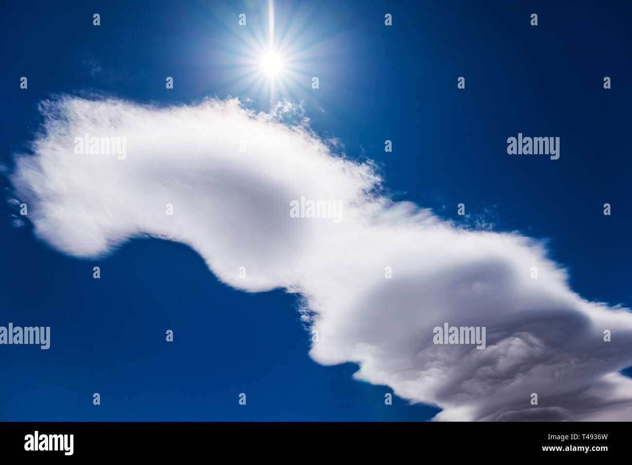 Sun burst & unusual cloud formations against clear cobalt blue sky ...