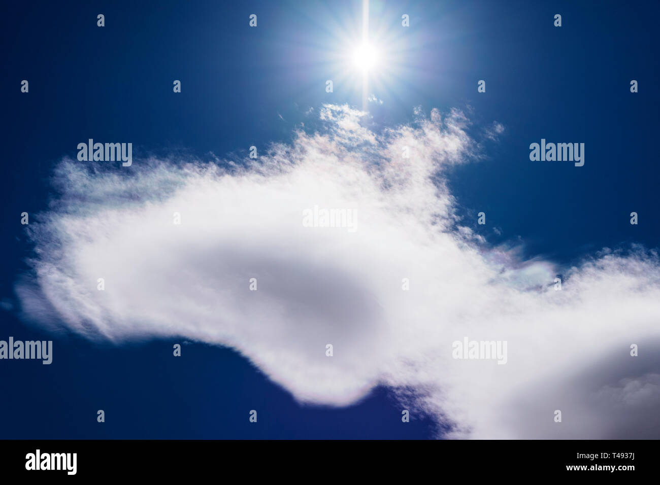 Sun burst & unusual cloud formations against clear cobalt blue sky ...