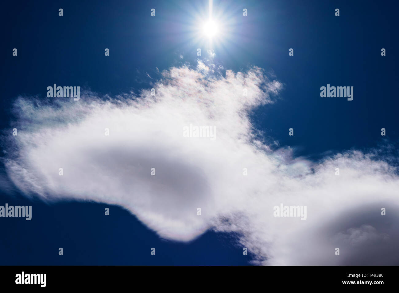 Sun burst & unusual cloud formations against clear cobalt blue sky ...