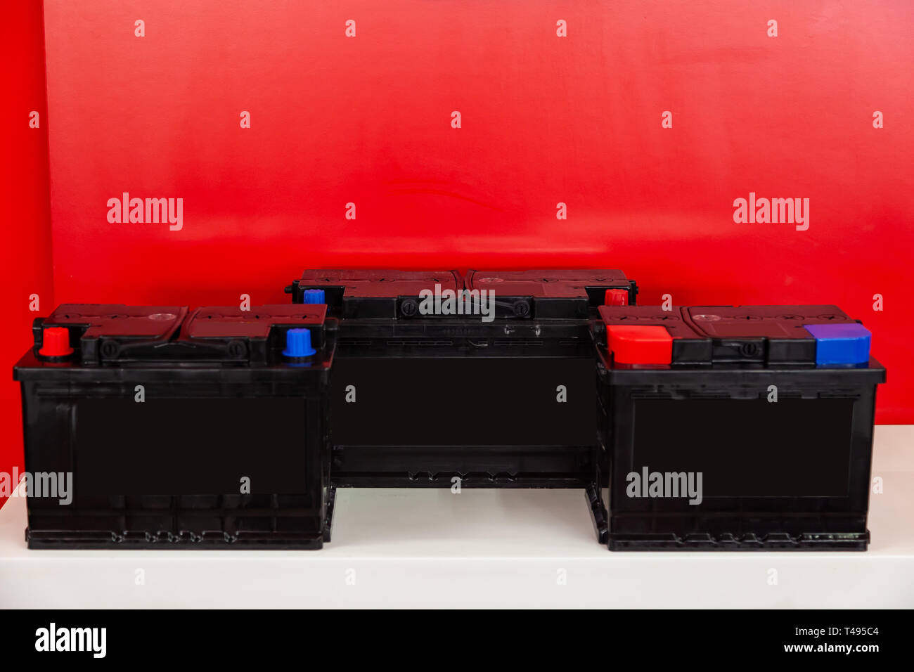 Three new black rechargeable batteries for car and vehicle stand on a ...