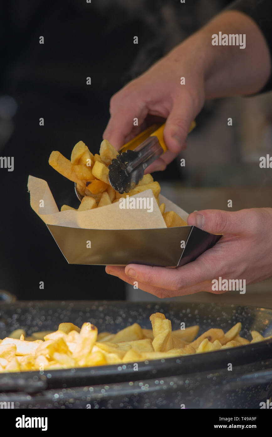 man serving chips into greaseproof paper and box Stock Photo - Alamy