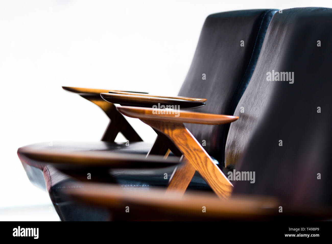 Close up of a couple of leather and wooden retro armchairs from belly ...