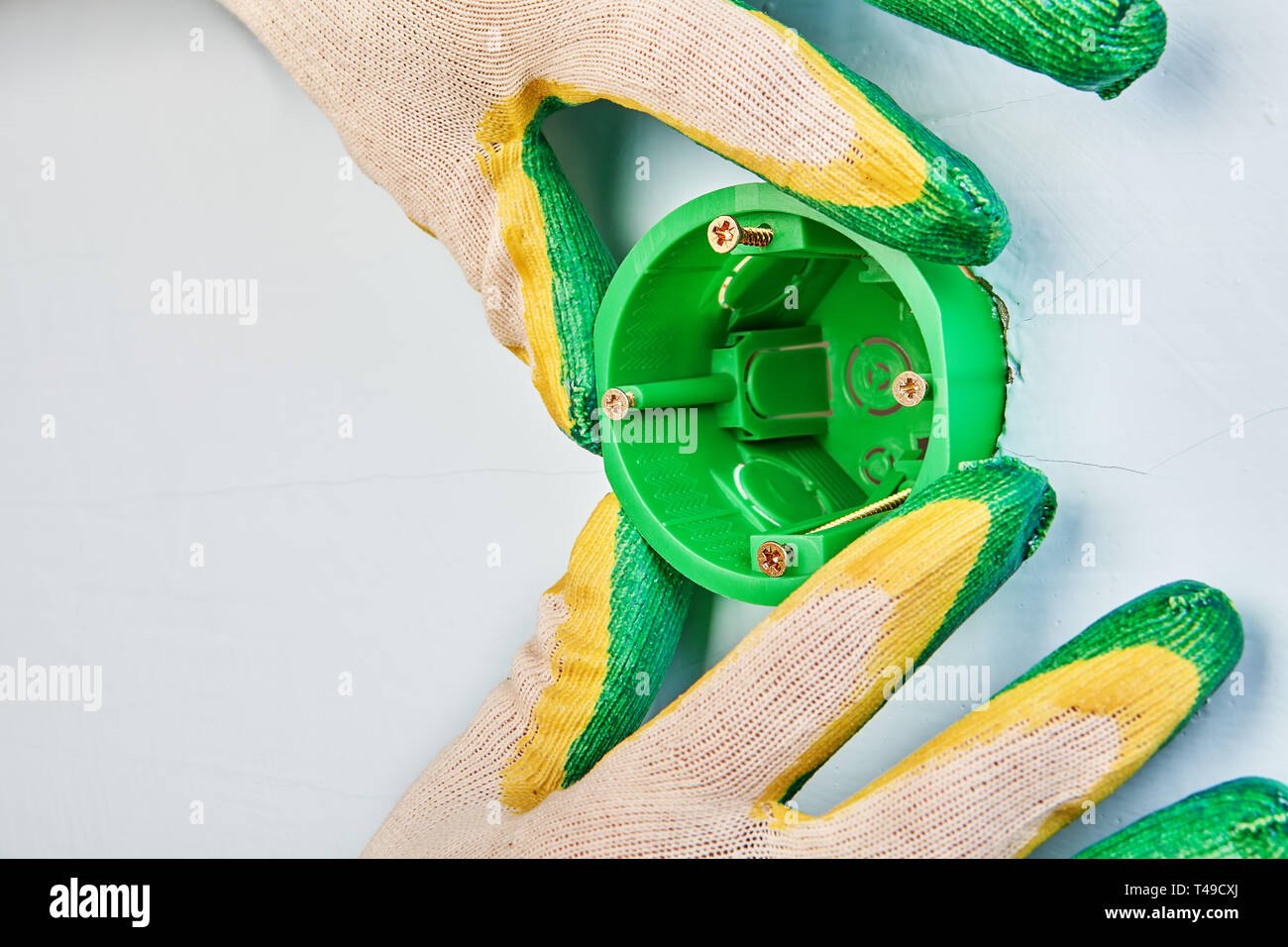 Electrician is making new switch or outlet wall electrical round box ...