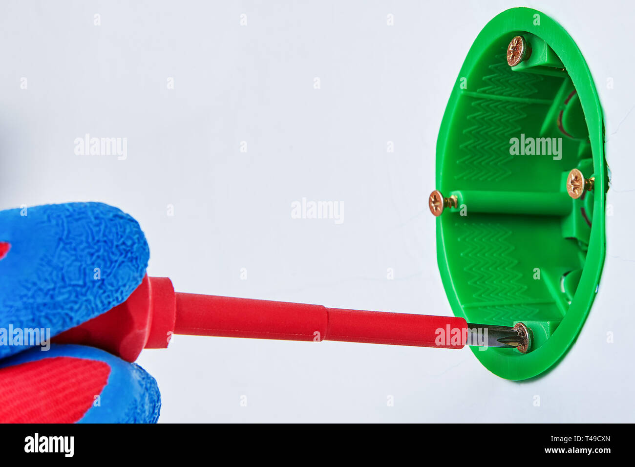 Electrician is tightening screw in round electrical box with help of ...