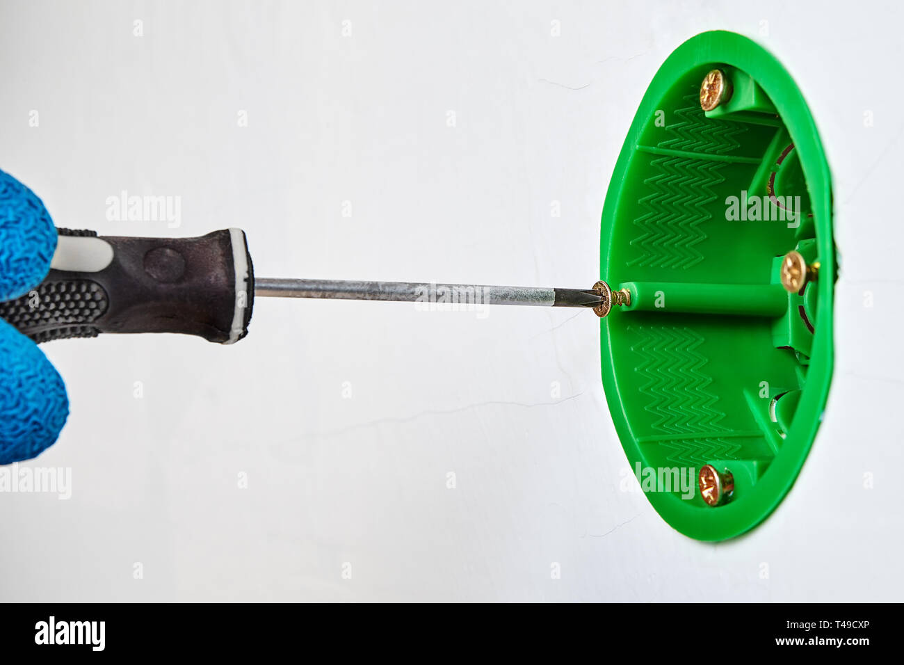 Worker is twisting screw in round electrical box with help of ...