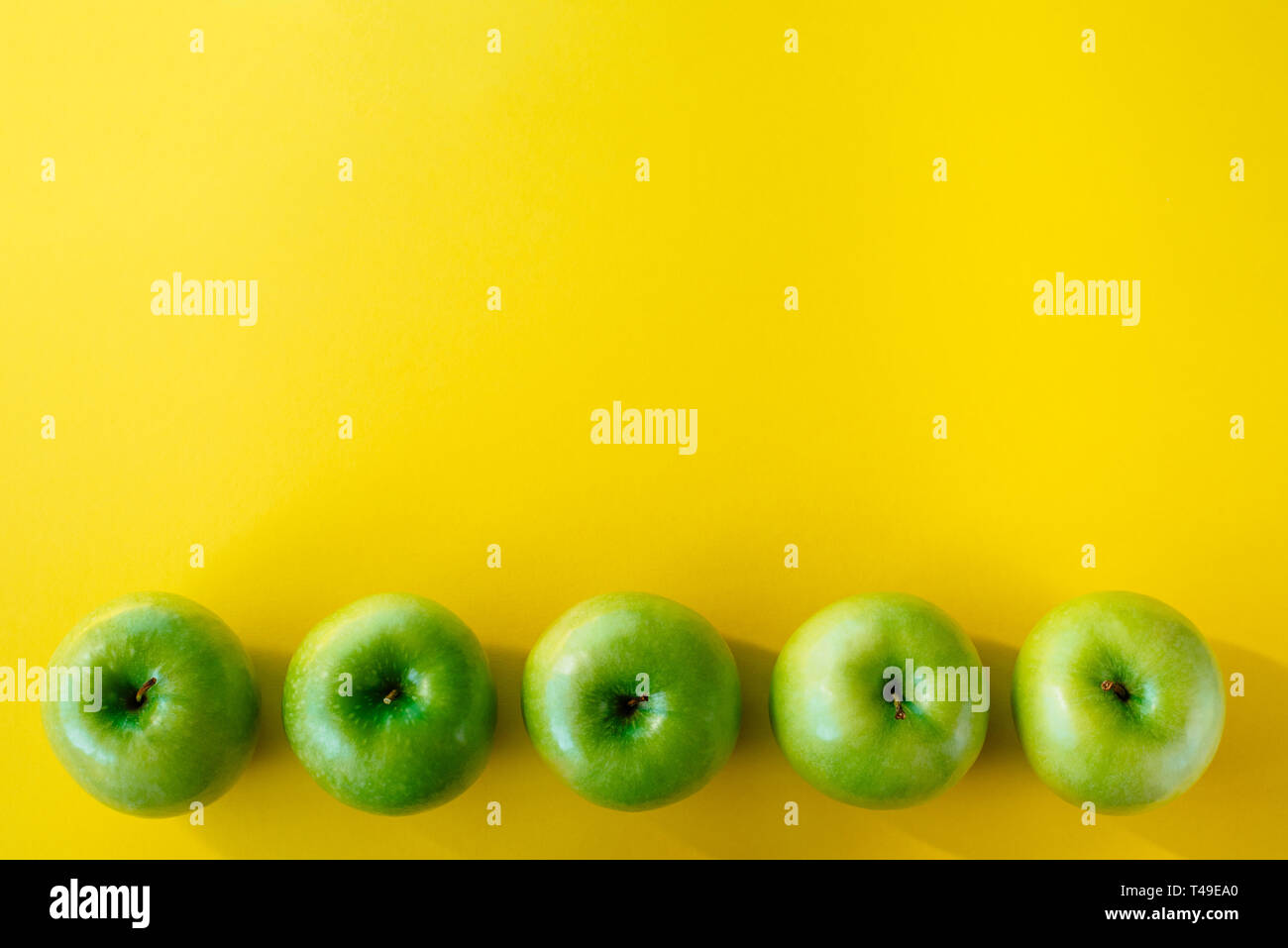 Summer pattern of fresh green apples on yellow background. Copy spase ...