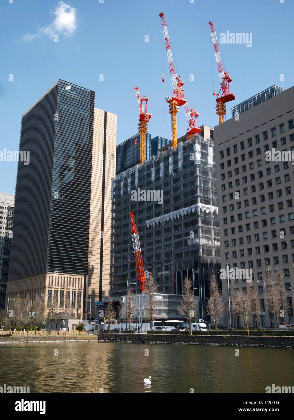 High rise buildings in construction with cranes on top of roof in Tokyo ...