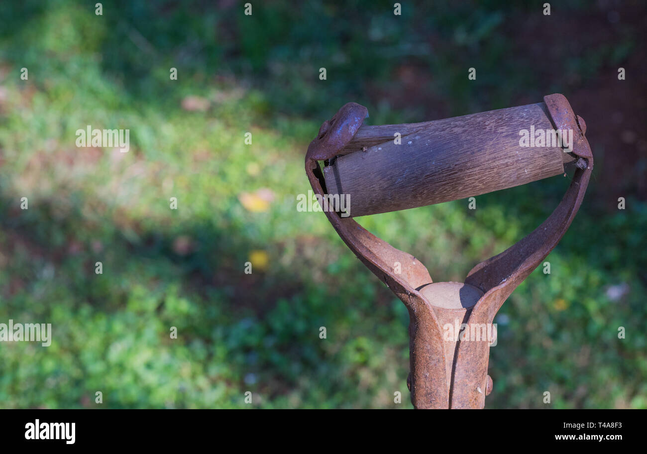 Damaged handle of a retro garden tool isolated against a green ...