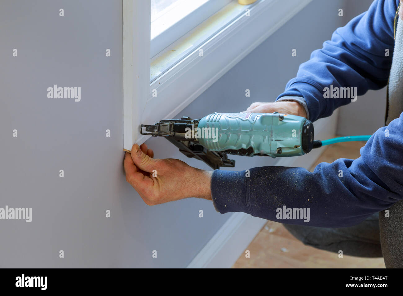 Carpenter using air nail gun to moldings for window, close up on hand ...