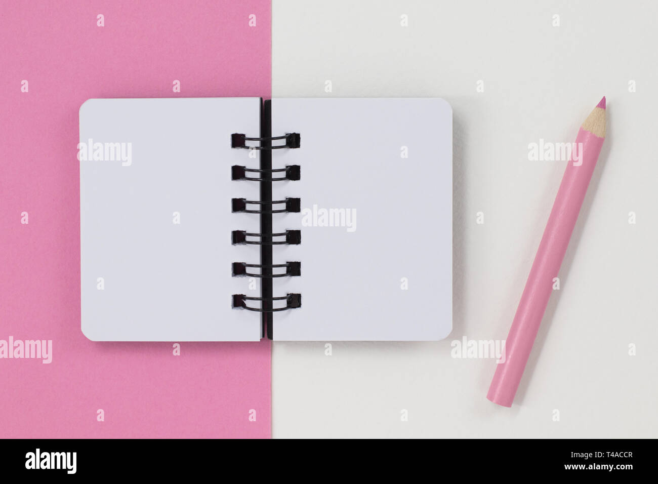 Open notebook and pink pencil, on pink and white background. Flat lay ...