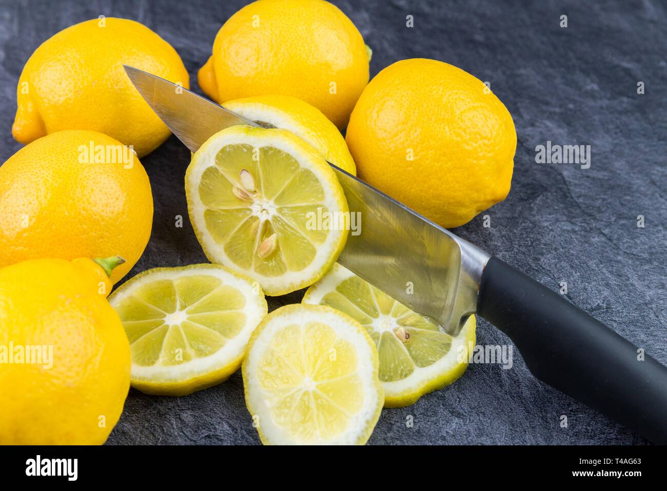 A sharp kitchen knife cuts a lemon into slices Stock Photo - Alamy