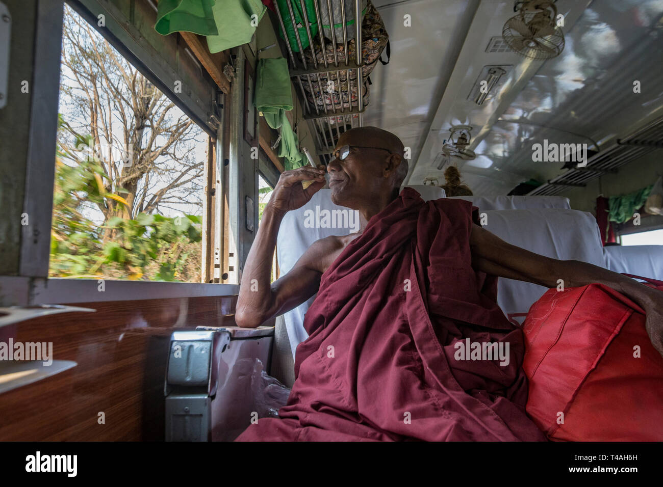 Buddhist monk smoking a cigarette on the Myanma Railways train from ...