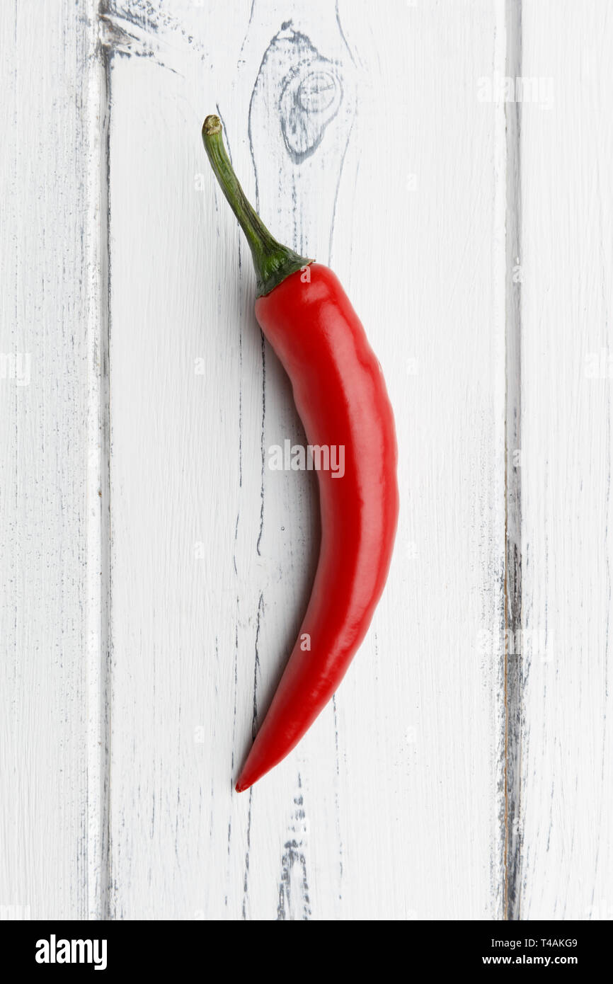 single red chilli on a distressed white wooden background Stock Photo ...