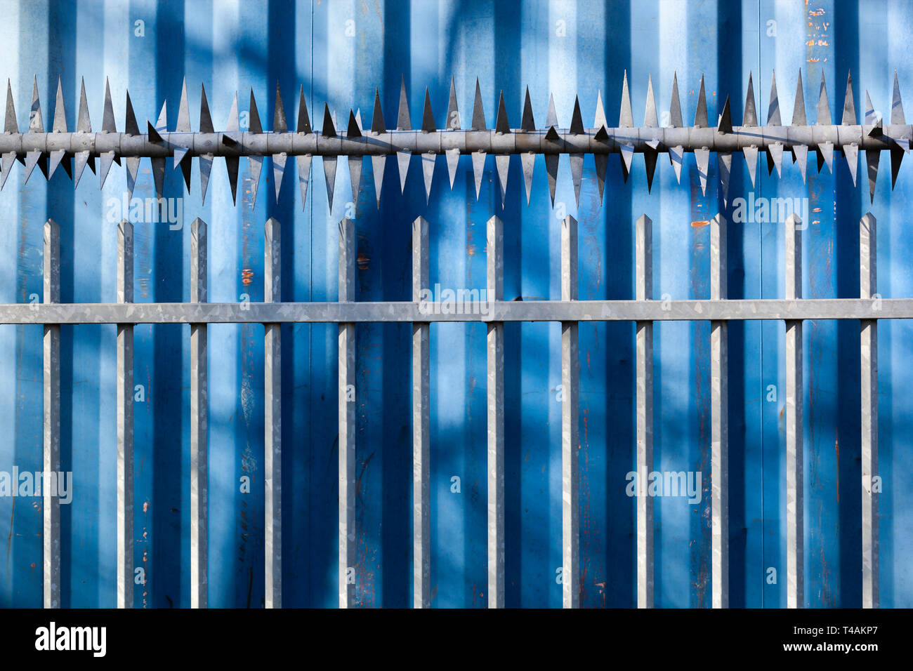 Blue cargo container behind a security fence with sharp spikes in the ...