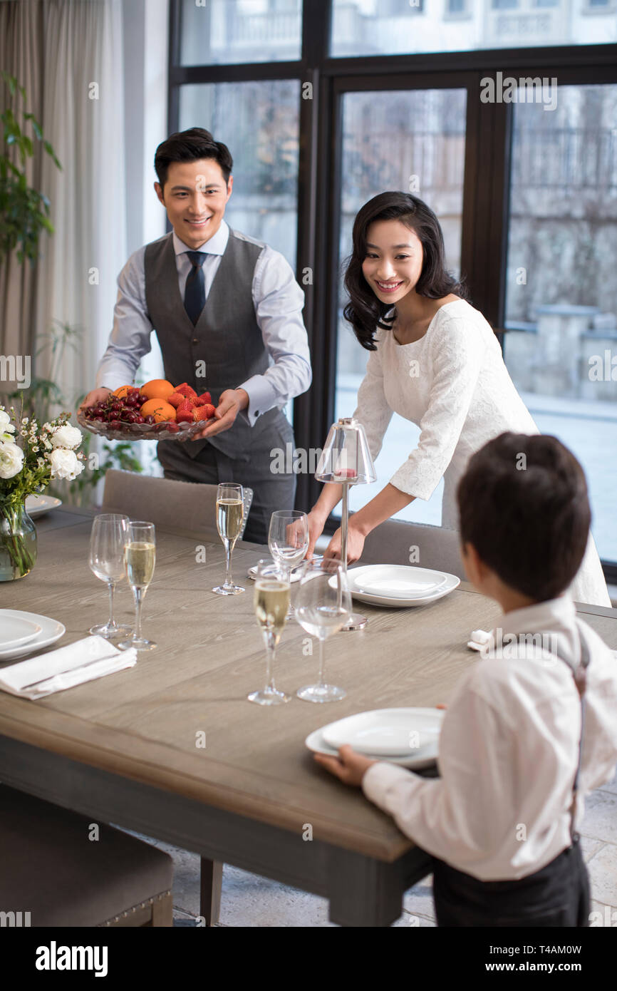Happy noble young family setting the table together Stock Photo - Alamy