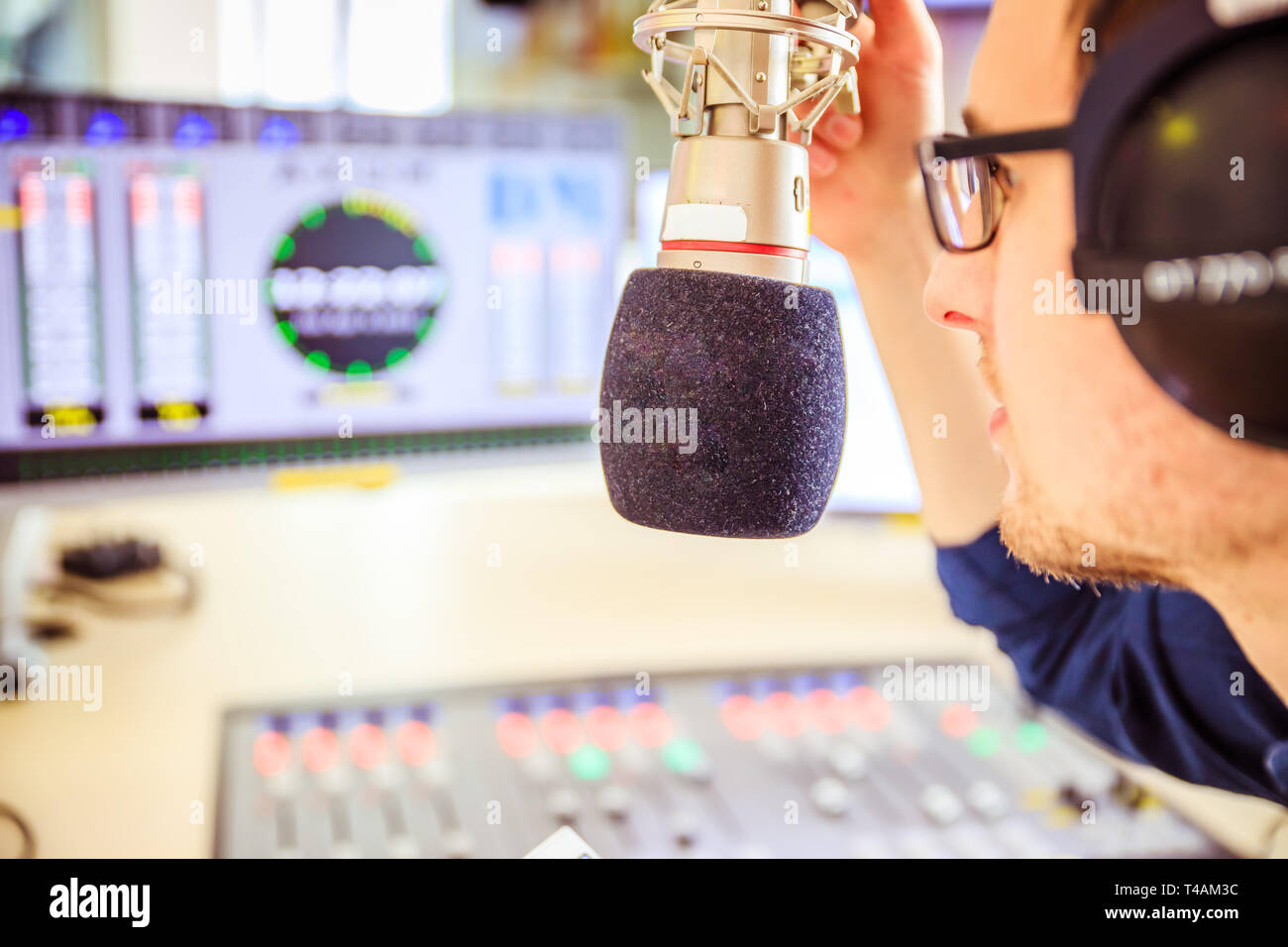 Young man in the broadcasting studio, radio, talking into the ...
