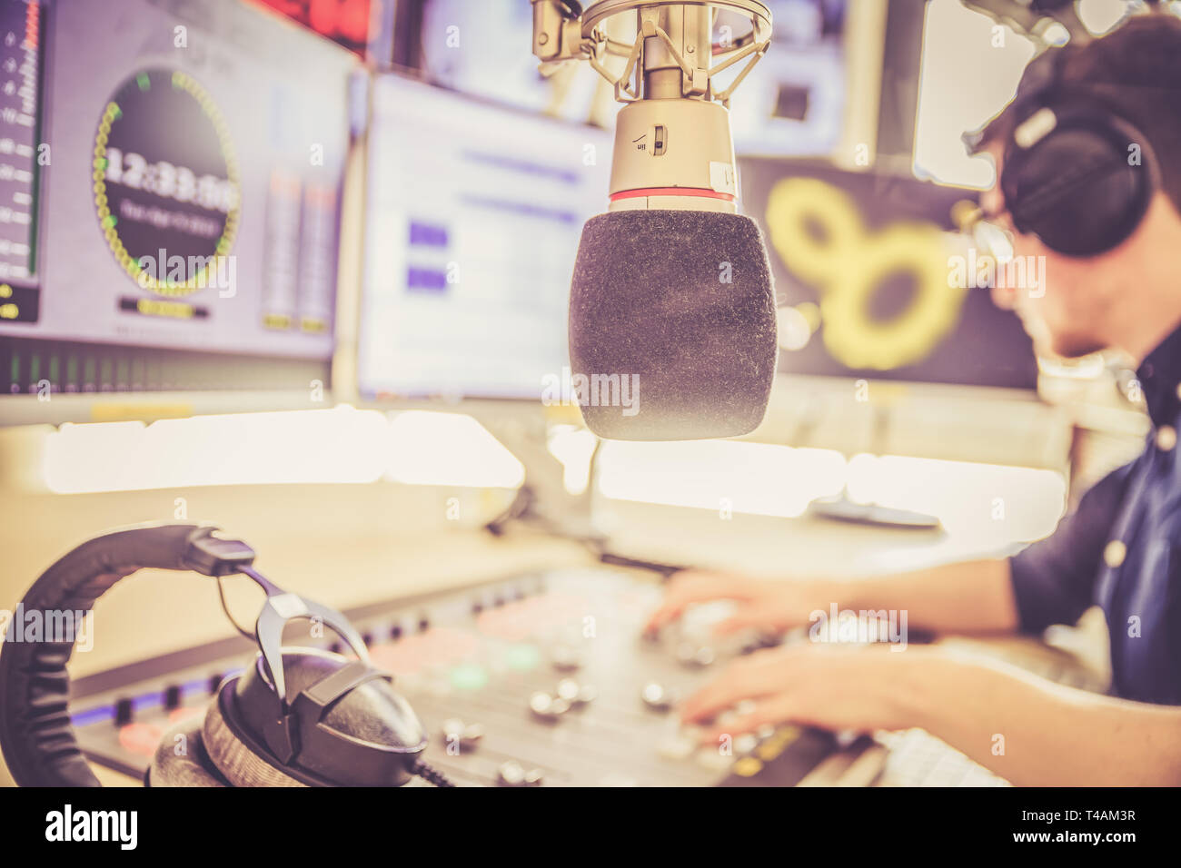 Young man in the broadcasting studio, radio, talking into the ...
