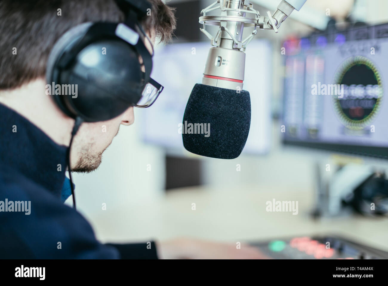 Young man in the broadcasting studio, radio, talking into the ...