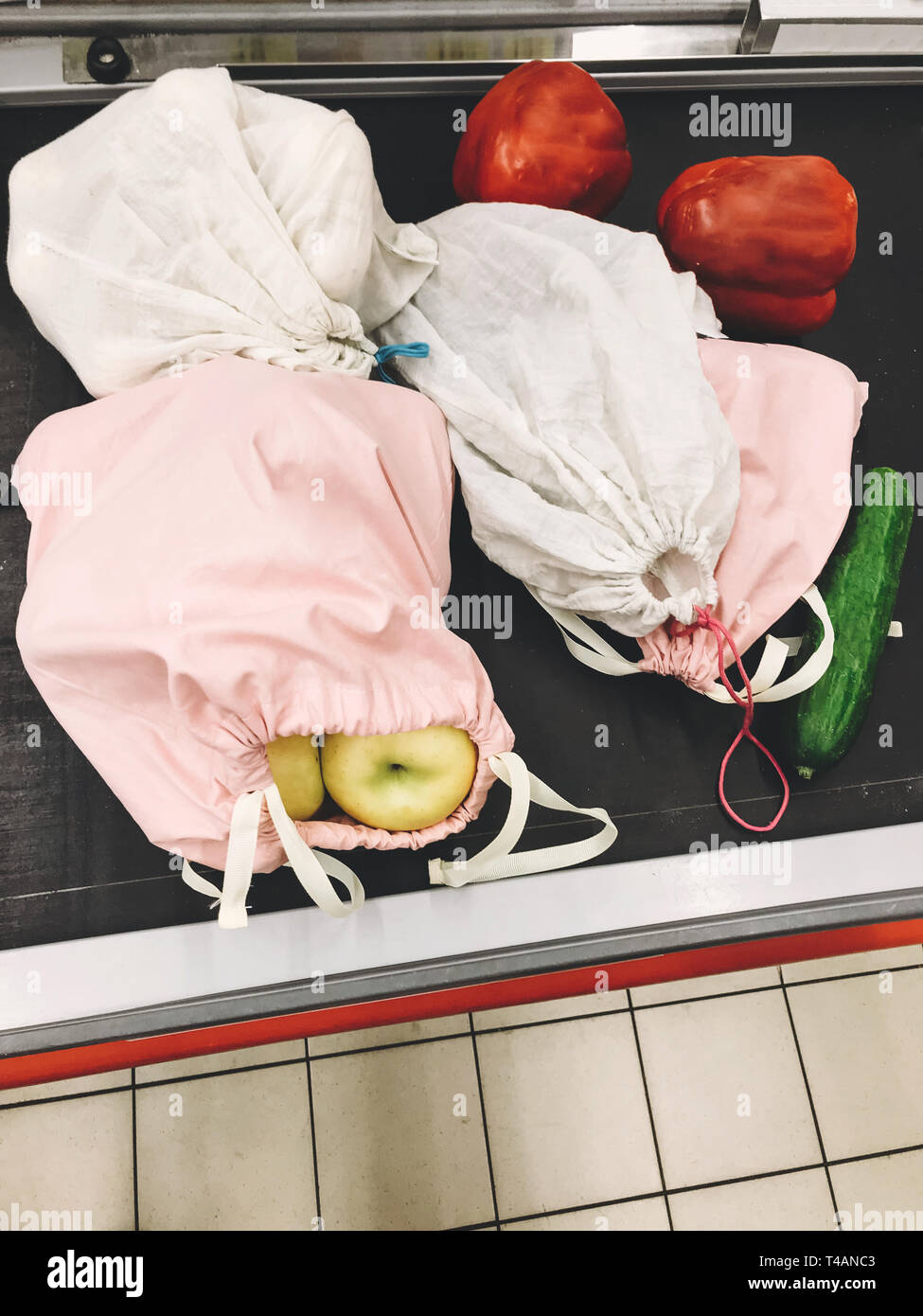 Eco reusable bags with vegetables and fruits on checkout counter line ...