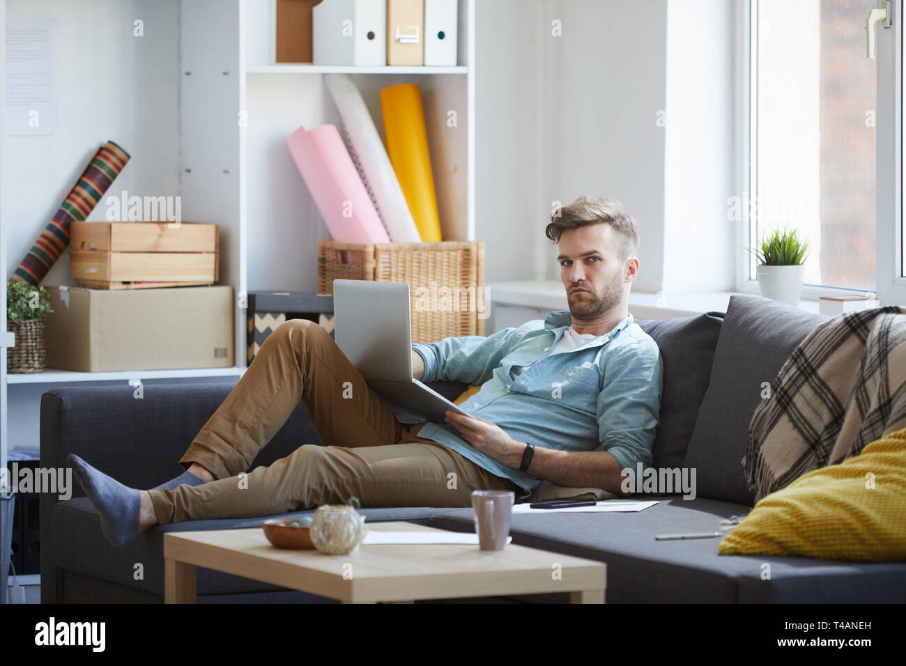 Handsome man sitting on sofa hi-res stock photography and images - Alamy