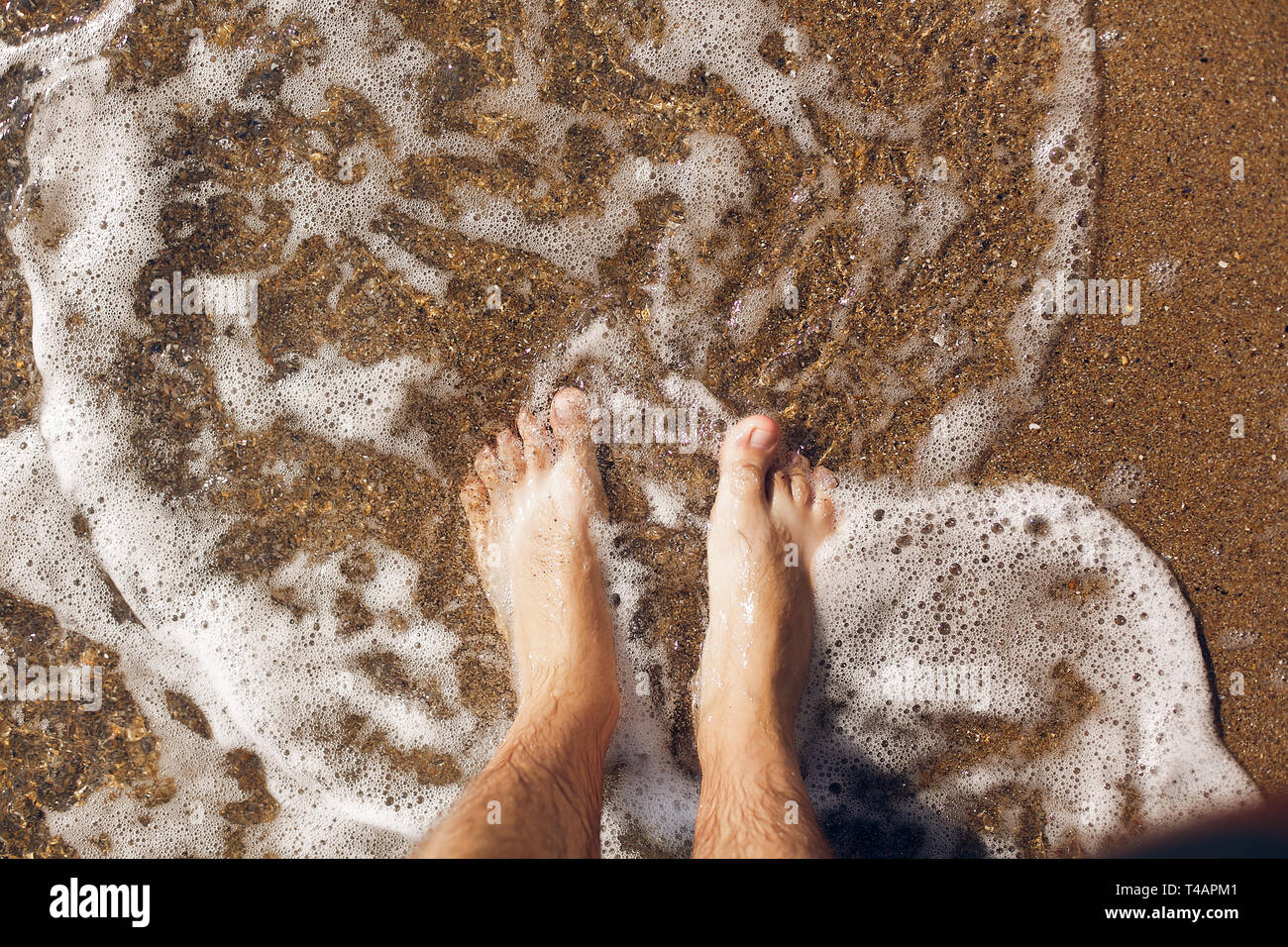 Top view of person feet in water on sandy beach and waves. Summer ...