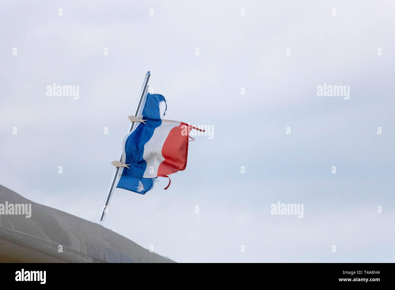 French flag all ripped and repaired with clothespins on a luxury boat ...