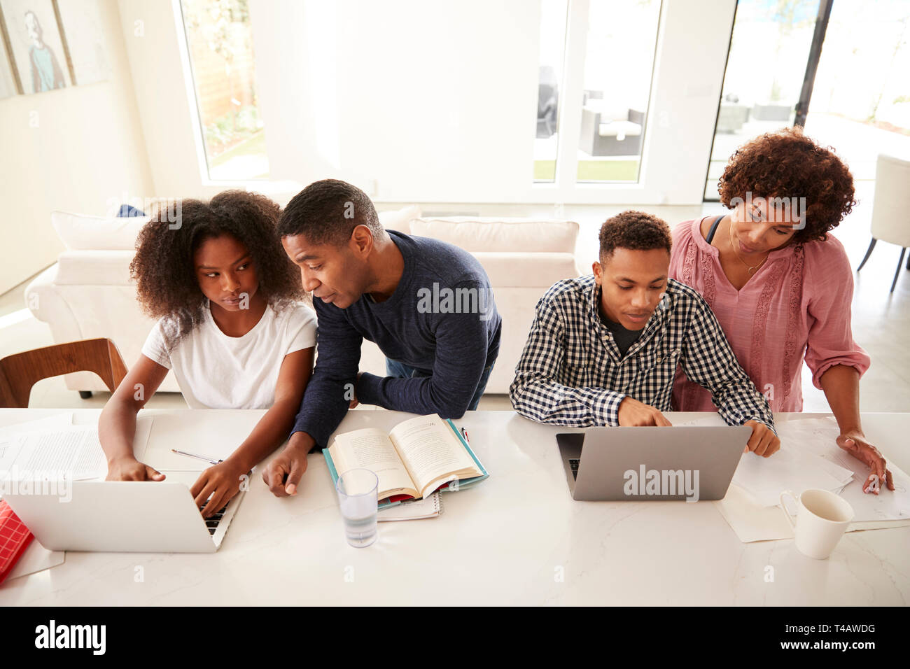 Middle aged black parents helping their teenage kids using laptops to ...