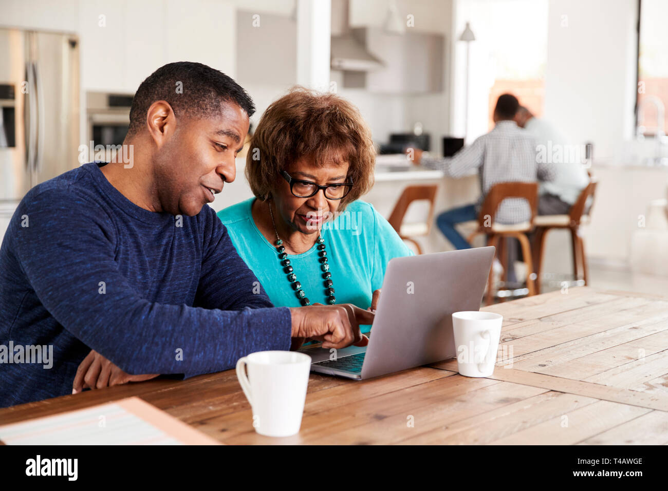 Middle aged black man helping his mother use a laptop computer at home ...