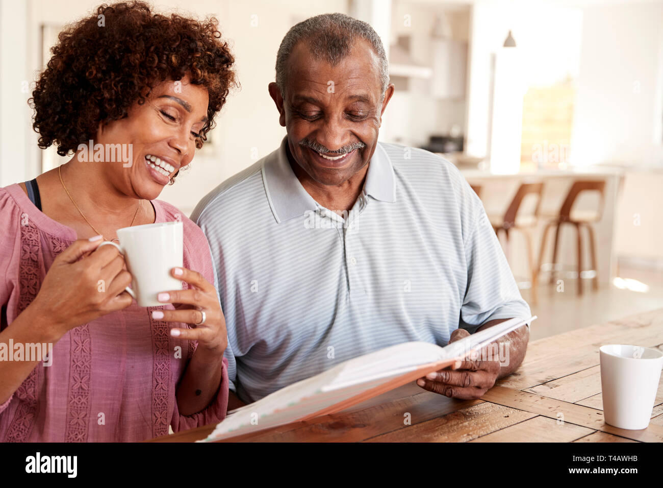 Middle aged black woman and her dad looking through photo album ...