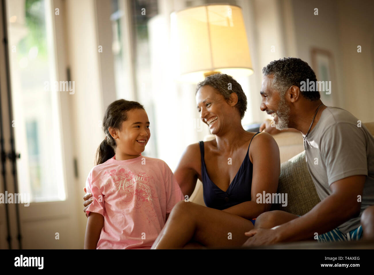 Parents laughing with daughter on couch Stock Photo - Alamy