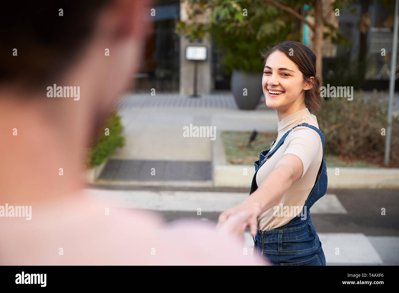 Over shoulder view of millennial couple crossing the road in the city ...
